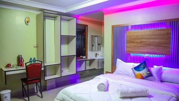 Quarto de hotel com cama, escrivaninha, cadeira e espelho.