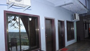 Um corredor com uma janela grande, uma porta e uma pequena mesa com um tabuleiro.
