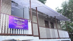 Um edifício com uma placa que diz "BABA HOUSE" e menção de uma aliança com "THE GRAND BAGICHA RESIDENCY".