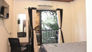 Quarto com cama, escrivaninha, cadeira, espelho e aparelho de ar condicionado.