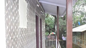 Um corredor coberto com paredes estampadas e chão de azulejos, que leva a uma área cercada com vegetação.