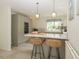 Uma cozinha moderna com dois banquetes, uma ilha grande e iluminação pendente.