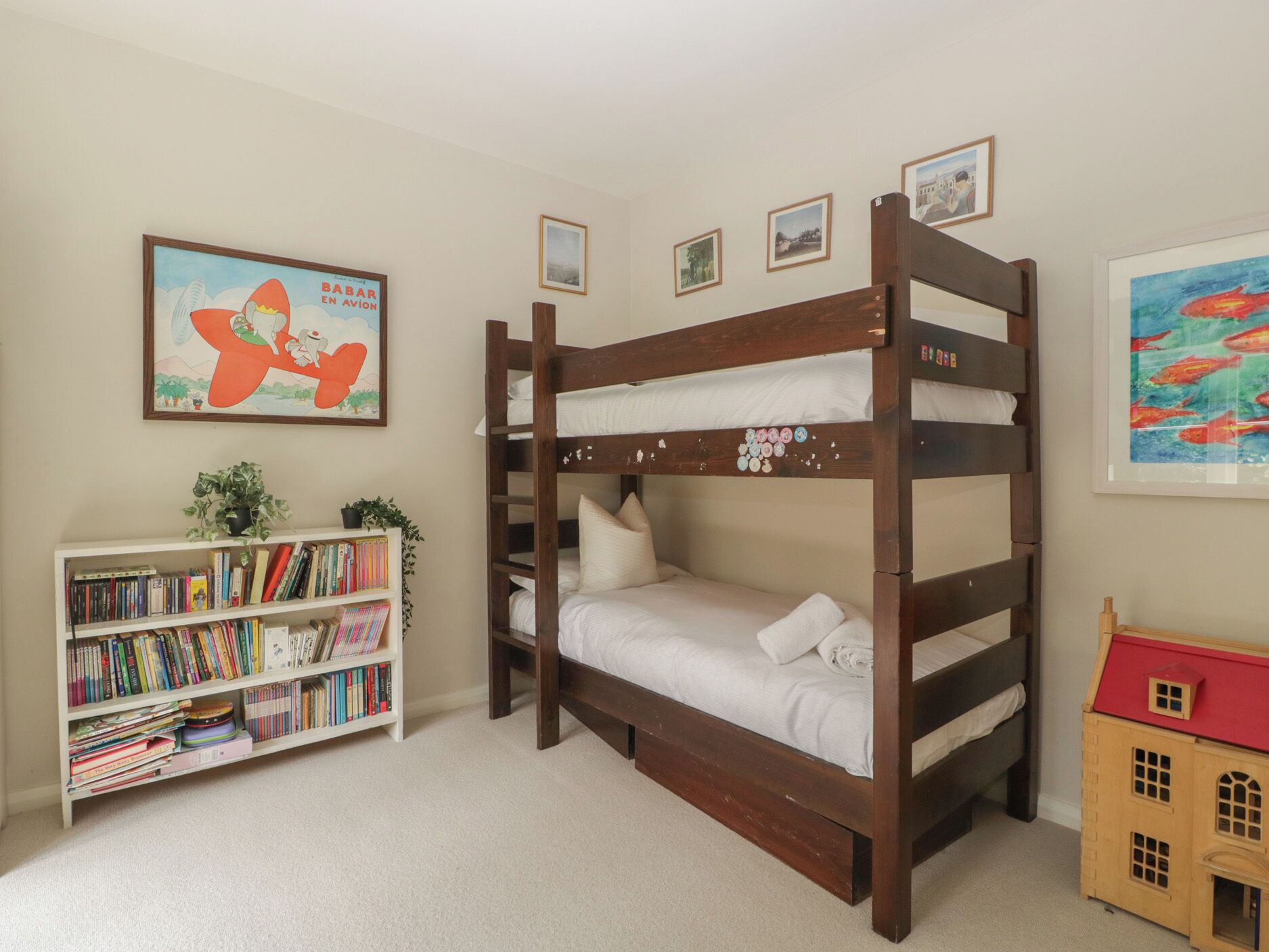 Quarto com beliche, uma estante e uma casinha de brinquedo.