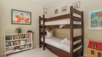 Quarto com beliche, uma estante e uma casinha de brinquedo.