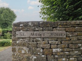Um muro de pedra com uma placa de madeira que diz 'St. Mary's House'.
