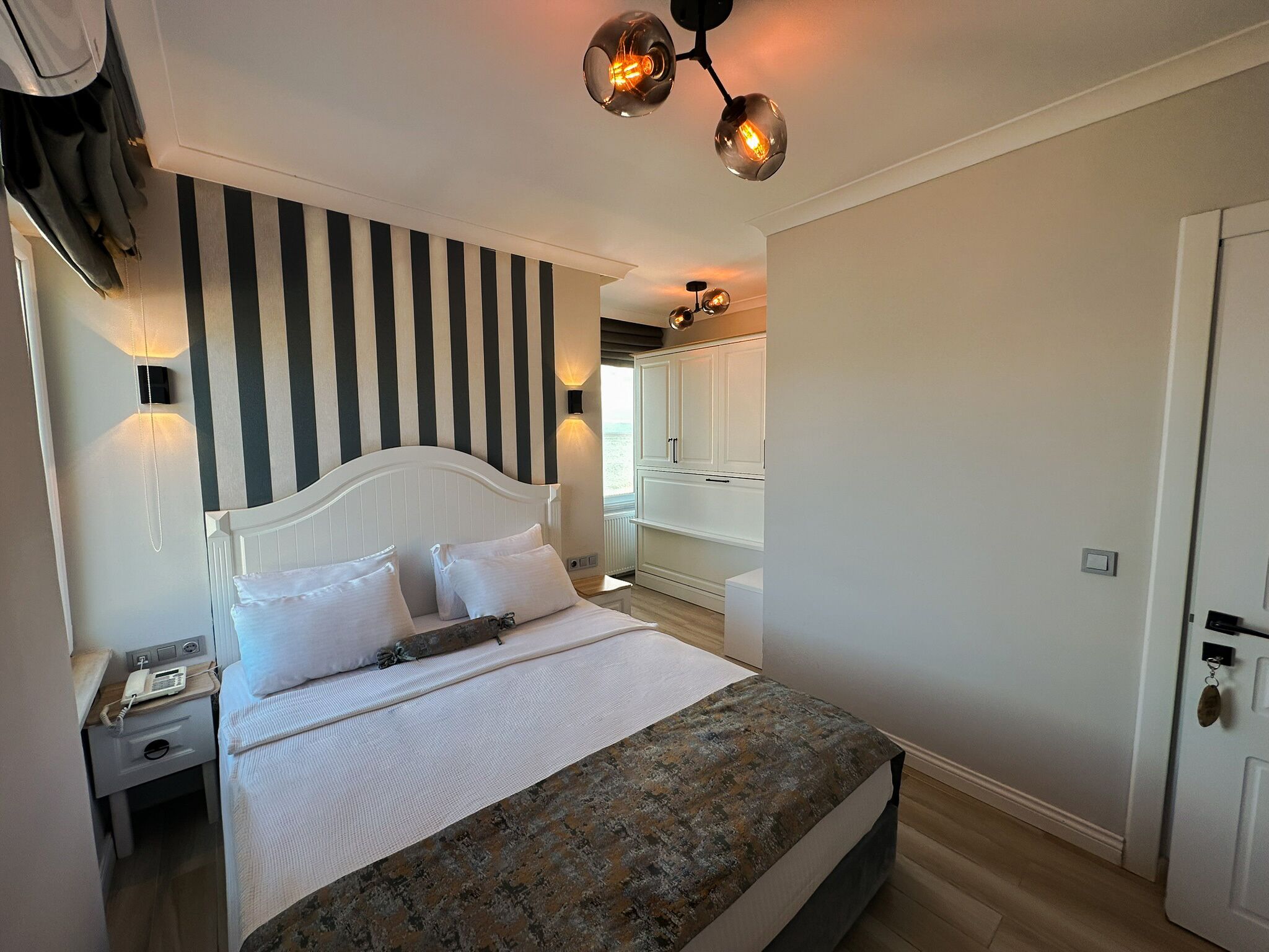 Quarto com cama, mesa de cabeceira, luminária e vista para um banheiro.