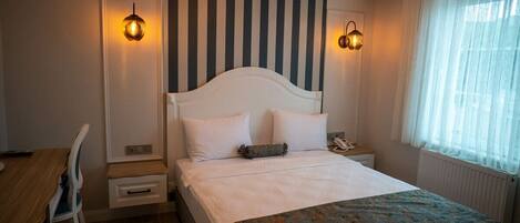 Quarto de hotel com cama, mesas de cabeceira, escrivaninha e uma cadeira.