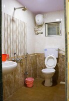 Casa de banho com sanita, chuveiro, lavatório e esquentador.