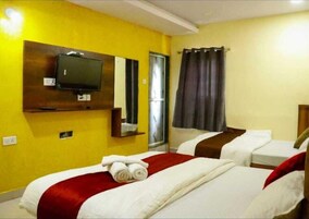 Quarto de hotel com duas camas, televisão fixada na parede e janela com cortinas.