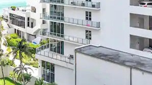 Um hotel com vários andares, varandas, janelas amplas e vista para a praia.