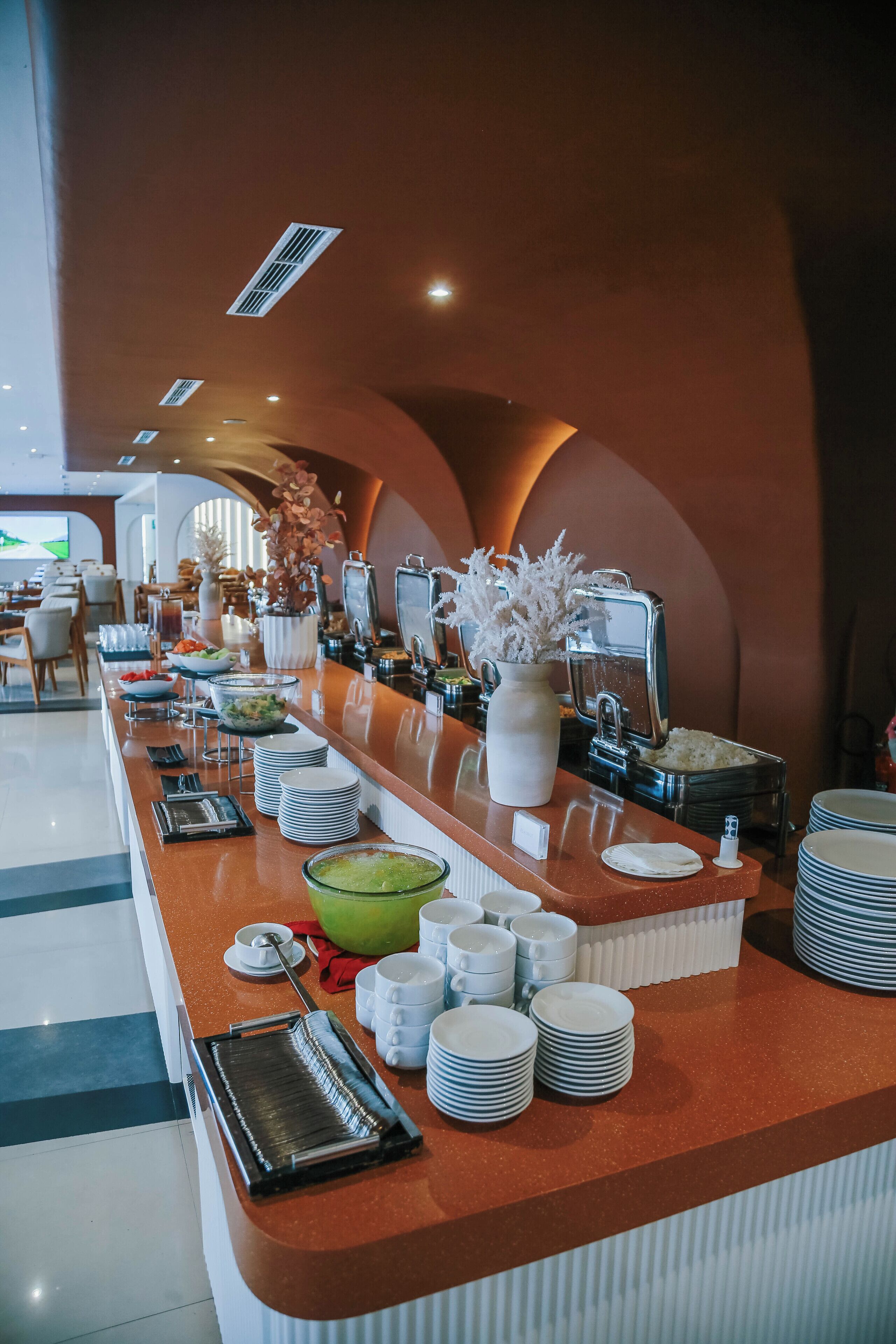Uma mesa de buffet com diversos alimentos, pratos e utensílios.