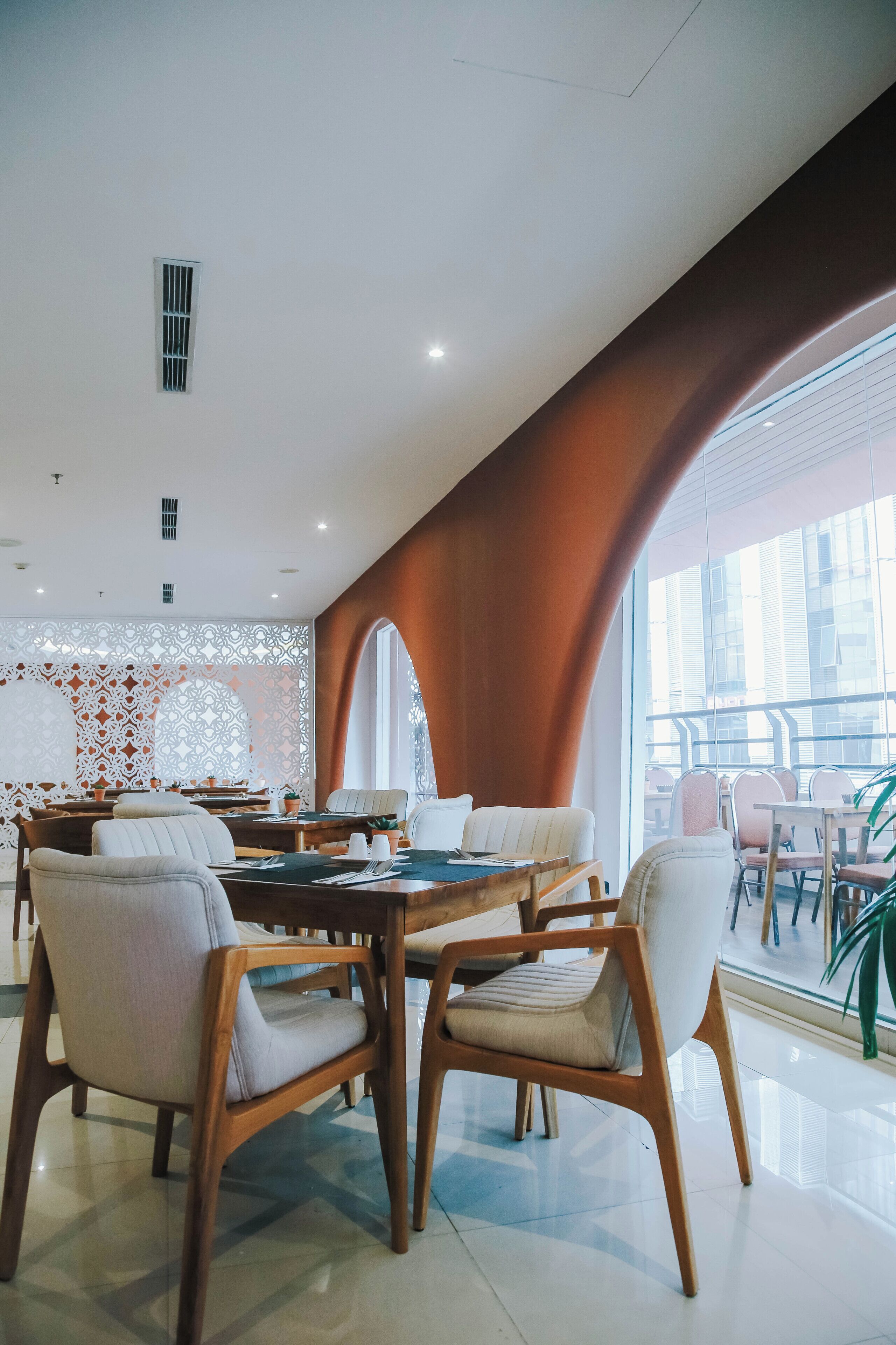 Uma sala de jantar moderna com teto alto, janelas amplas e um painel decorativo.
