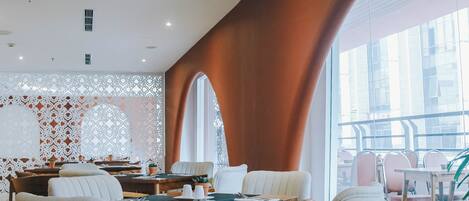 Uma sala de jantar moderna com teto alto, janelas amplas e um painel decorativo.