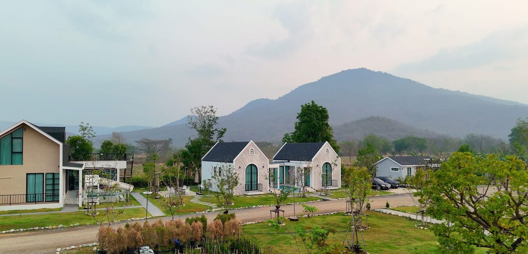 Zona residencial com casas modernas, gramado bem cuidado e uma montanha ao fundo.