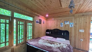 Quarto com painéis de madeira, cama, janelas amplas e teto de madeira.