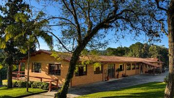 Um edifício de dois andares com telhado de telhas vermelhas, entrada com calçada e gramado bem cuidado.