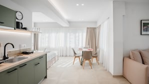 Cozinha moderna com área de refeições, sofá e janela com cortinas.