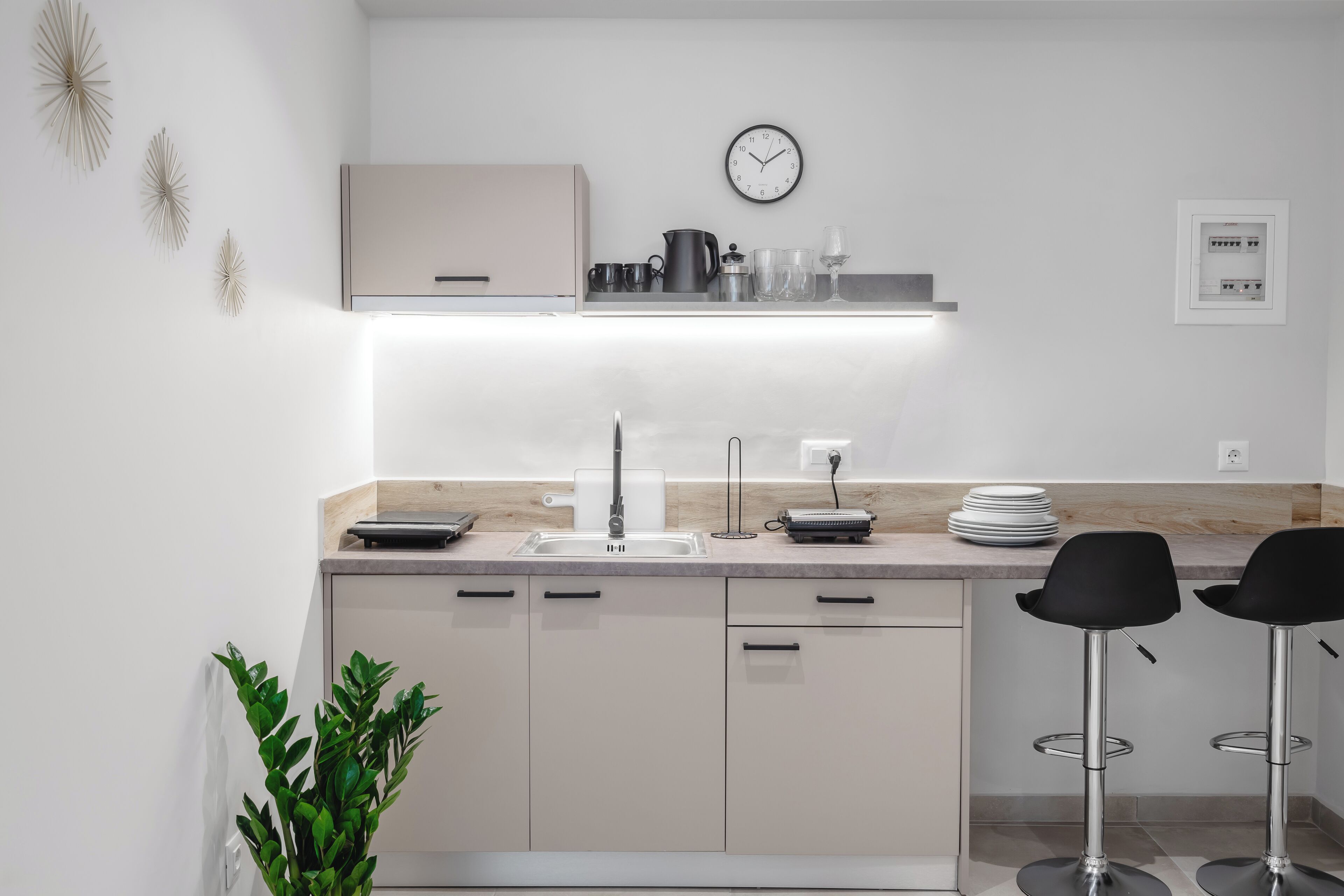 Cozinha moderna com pia, bancada e dois bancos altos.