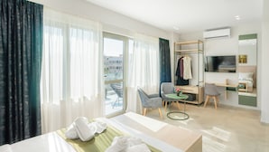 Quarto de hotel com cama, escrivaninha, cadeira, televisão e vista para o exterior.