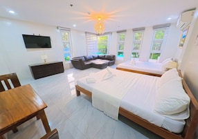 Quarto com cama, escrivaninha, sofá e televisão.