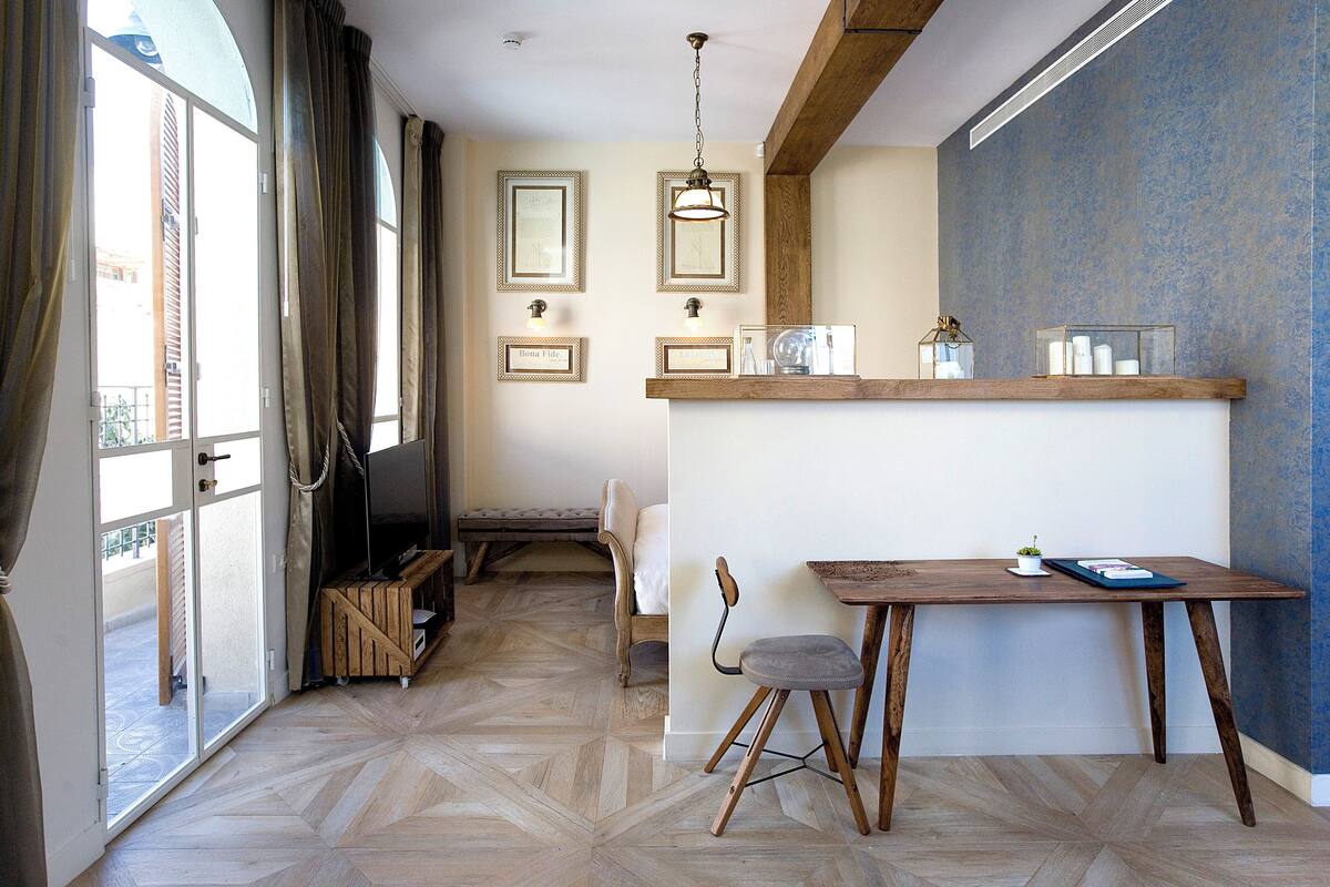 Quarto moderno com uma mesa de jantar de madeira, uma cadeira e uma pequena estante com velas e uma planta.