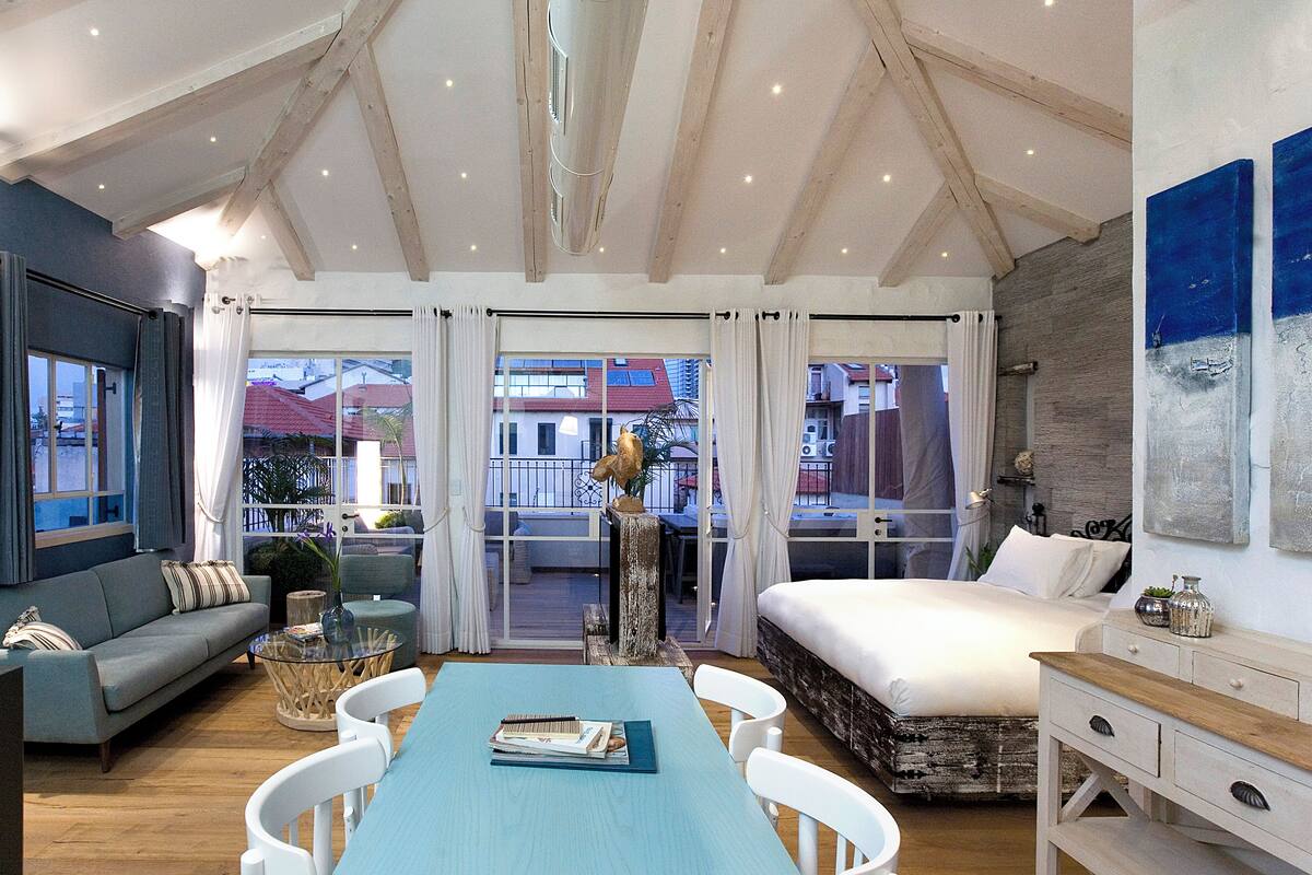 Quarto espaçoso com uma cama grande, um sofá, uma mesa de jantar e vista para o exterior.