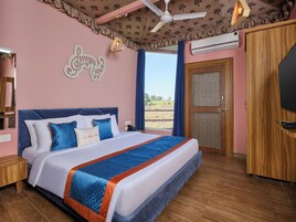 Quarto com cama grande, ventilador de teto, ar condicionado e vista para o exterior.