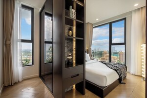 Quarto moderno com uma cama grande, um guarda-roupa embutido e vista para a cidade.