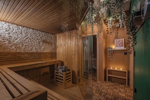 Uma sauna de madeira com bancos, porta de vidro e prateleira com velas.