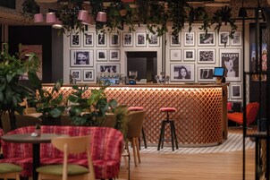 Uma área de bar com parede estampada, quadros emoldurados e banquetas.