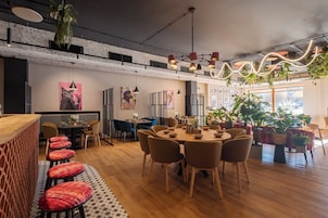 Uma área de refeições moderna com mesa de madeira, várias cadeiras e um balcão com banquetas.