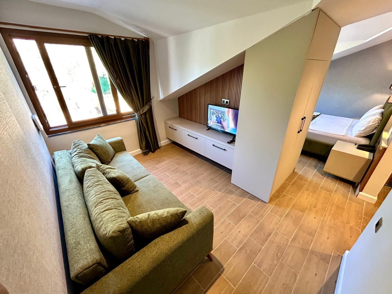 Um espaço de estar compacto com sofá, televisão e cama.