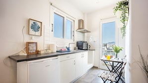 Cozinha moderna com armários brancos, bancada preta e janela com vista para a cidade.