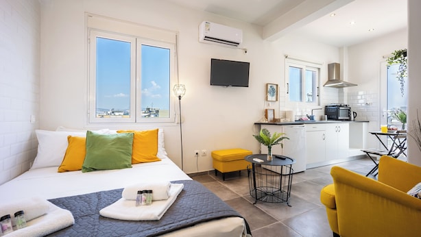 Quarto de hotel moderno com cama, pequena cozinha e mesa de jantar.