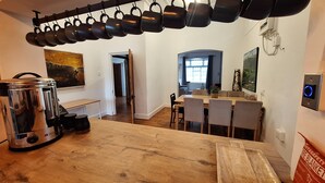 Uma cozinha com bancada de madeira, cafeteira e um suporte para panelas suspenso.
