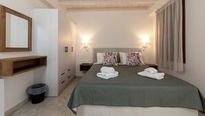 Quarto com uma cama, duas mesas de cabeceira, um criado-mudo, um espelho, uma estante de madeira, um cesto de lixo e uma janela com cortinas.