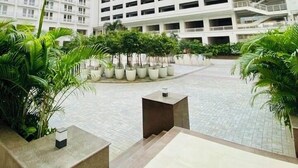 Um edifício de vários andares com design moderno, apresentando um pátio central com plantas em vasos e algumas áreas de estar.
