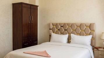 Um quarto com cama, guarda-roupa e mesa de cabeceira.