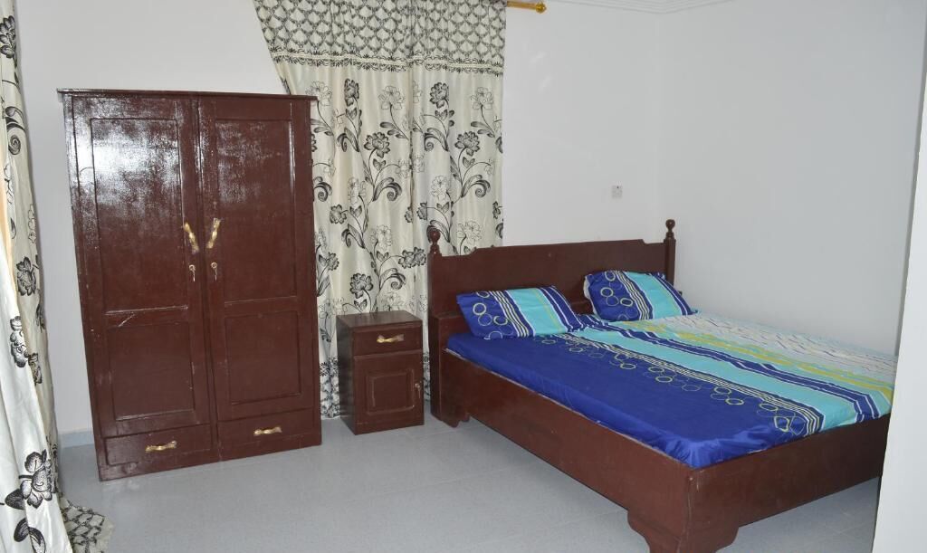 Quarto com cama de madeira, guarda-roupa e mesa de cabeceira.