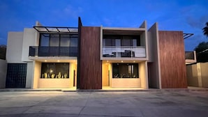 Uma casa moderna de dois andares com varanda, janelas amplas e calçada de concreto.