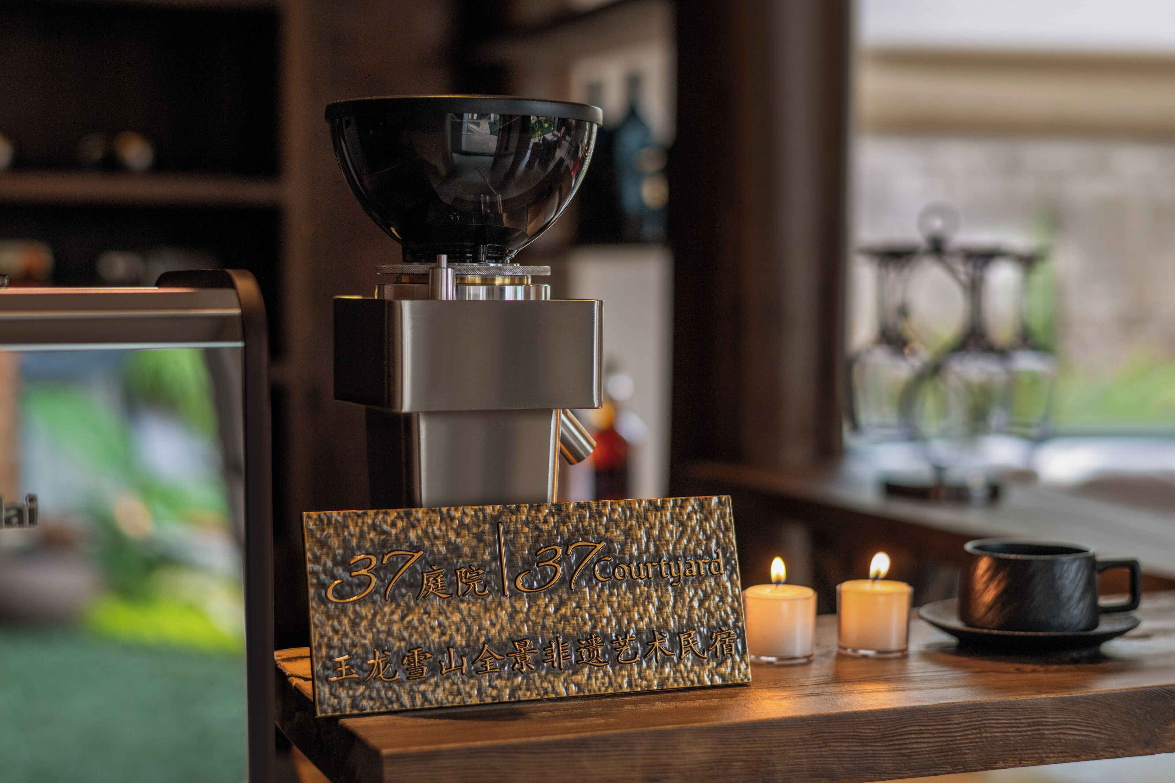 Máquina de café em bancada, com um letreiro que diz "37 Courtyard" e uma vela.