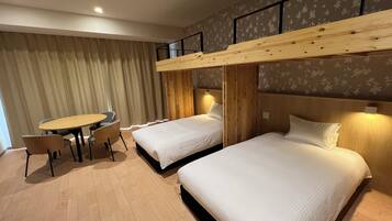 Quarto de hotel com duas camas, uma mesinha e cadeiras.