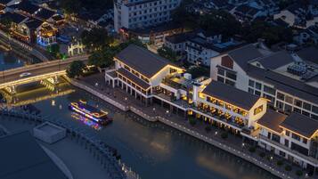 Um hotel às margens do rio, com vários andares, uma galeria coberta e um cais para barcos.