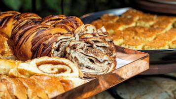 Uma bandeja com diversos doces, incluindo um rolinho de canela e um pastel assado, apresentada em uma bandeja de cobre.