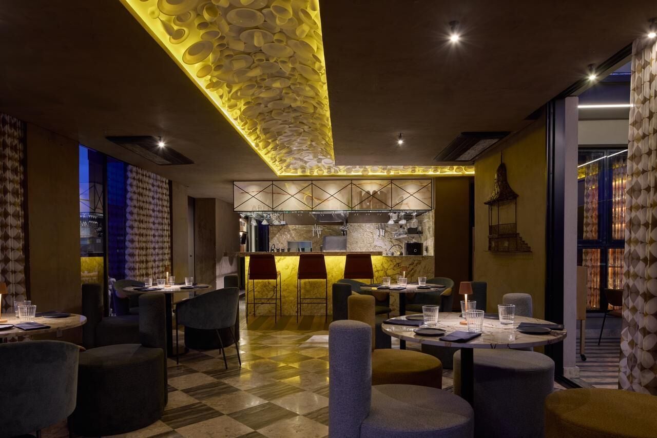 Um restaurante moderno com chão xadrez, área de bar e um design de teto único.