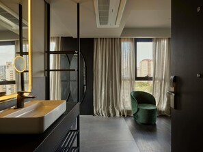 Uma casa de banho moderna com um espelho grande, uma pia e uma cadeira verde.