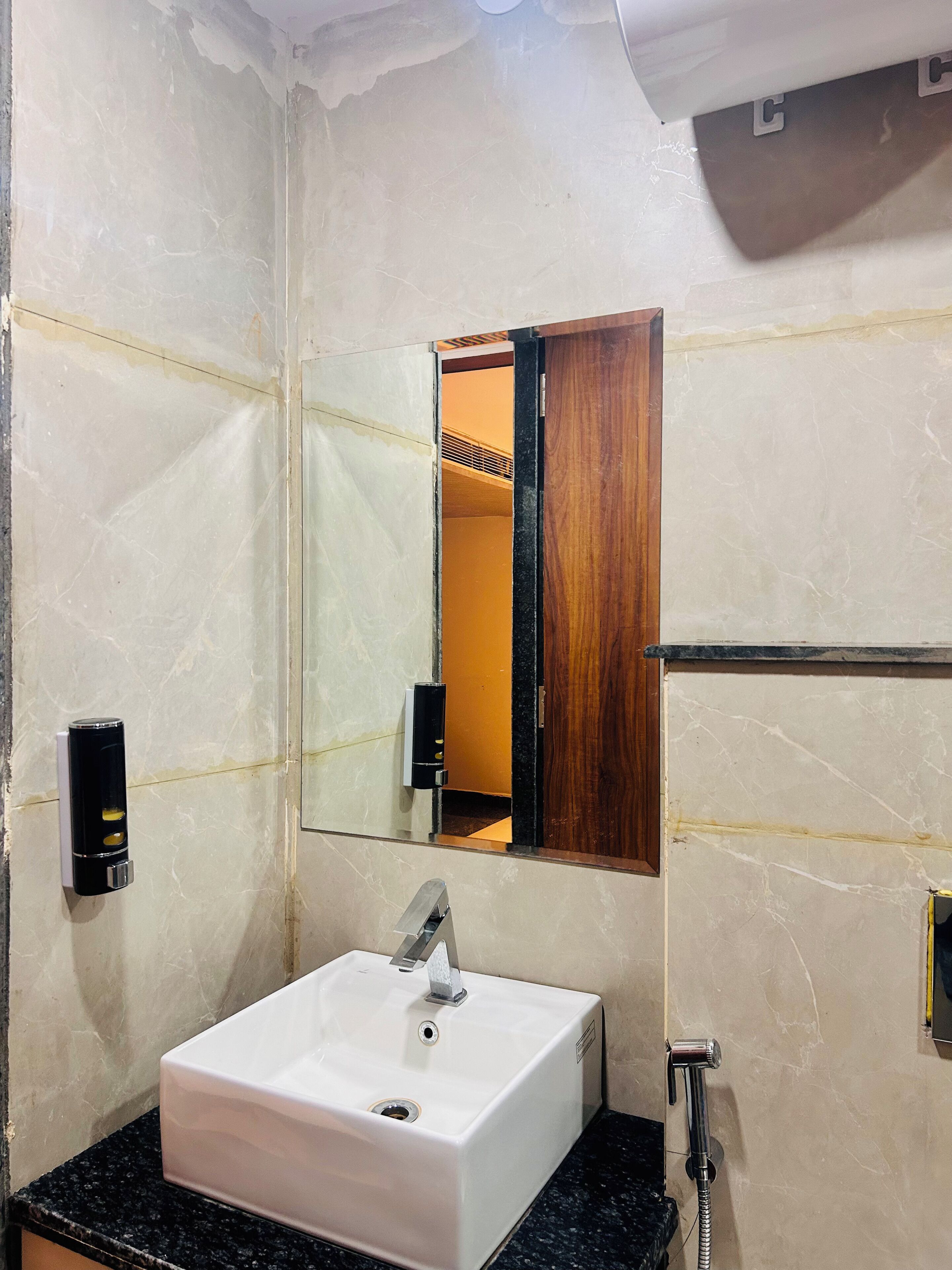 Uma casa de banho com uma pia branca, um espelho, um porta-toalhas e um chuveiro.