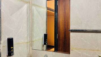 Uma casa de banho com uma pia branca, um espelho, um porta-toalhas e um chuveiro.