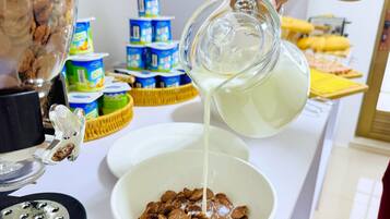 Uma mão despejando leite numa tigela de cereal.