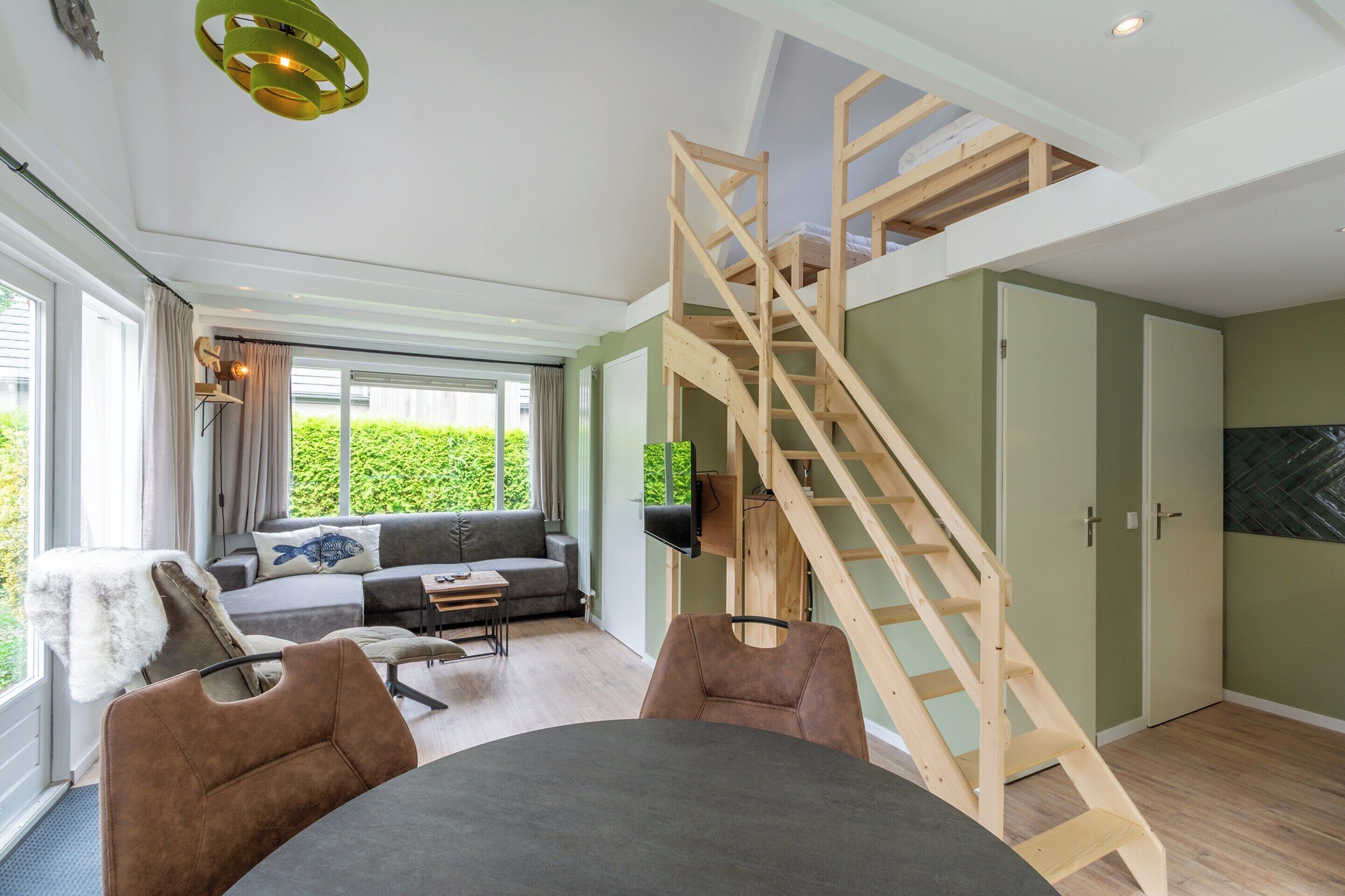 Uma sala de estar moderna com escada de madeira, um conjunto de sofá e uma mesa de jantar.